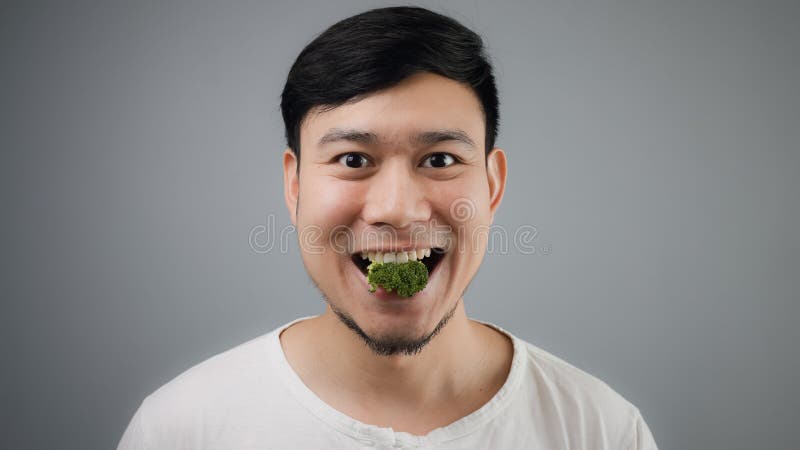 An Asian Man Eats Broccoli. Stock Image - Image of holding, food: 57158733