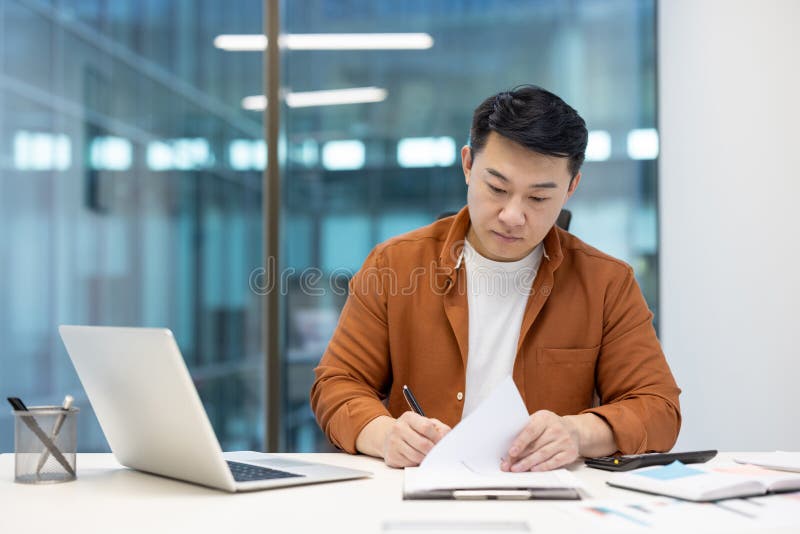 Asian Man Focusing at Work on Documents in a Professional Office ...