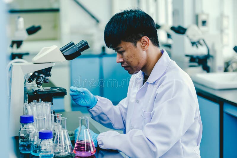 Asian Man Lab Technician in Protective Glasses and Gloves Sits Next To ...