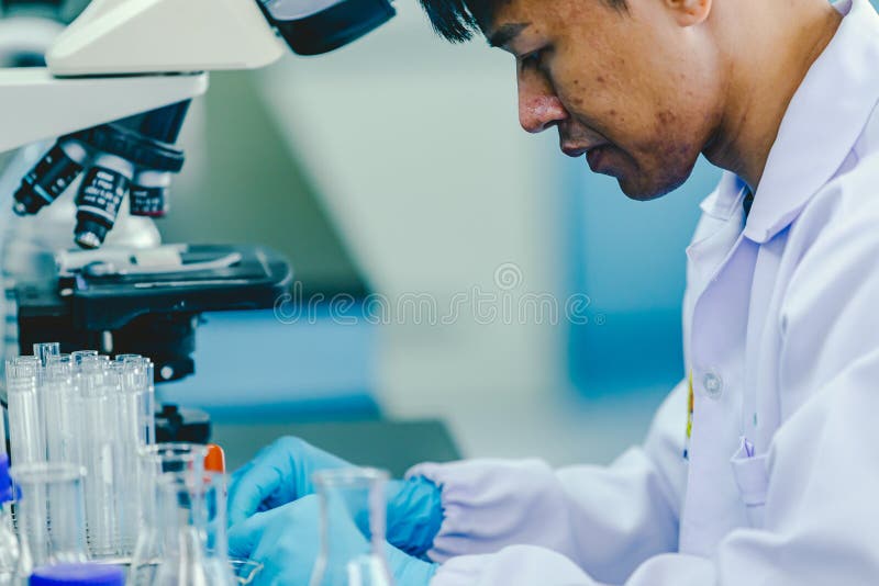 Asian Man Lab Technician in Protective Glasses and Gloves Sits Next To ...