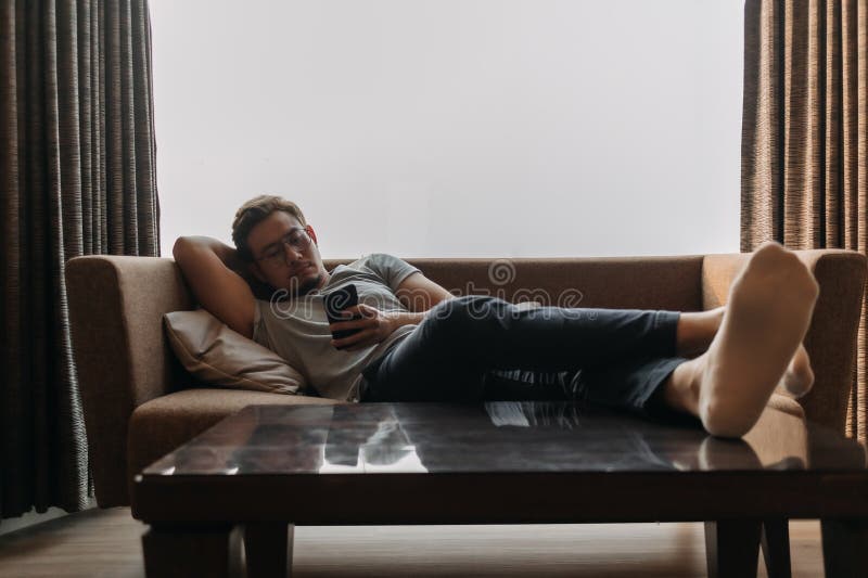 Man Lies on Sofa Using Phone with His Feet on the Table. Concept of ...