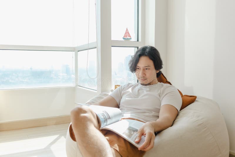Man Relax and Reading Book on Bean Bag Sofa in His Apartment. Stock ...