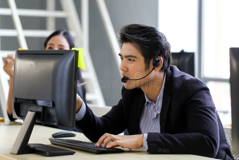 Asian Man Serious Call Center Operator in Wireless Headset Talking with ...