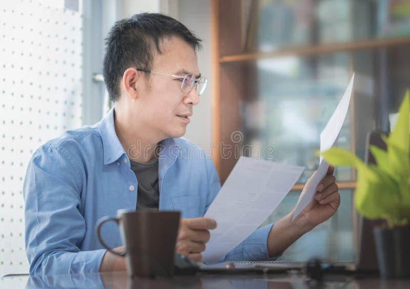 Asian Man Sitting at Table Drink Coffee Working with Documents and Laptop in Home Stock Photo ...