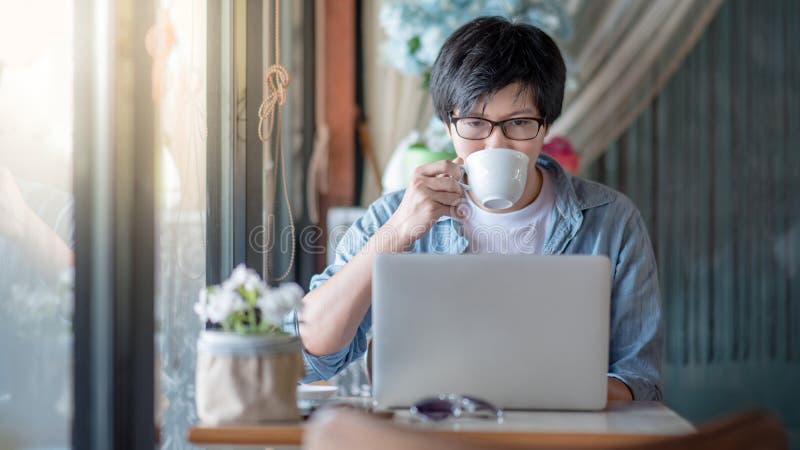 Asian Man Using Laptop Computer while Drinking Coffee Stock Photo ...