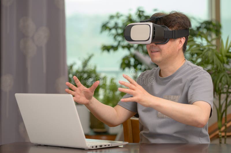 Asian Man Wearing VR Headset and Using Laptop while Sitting at His Desk ...