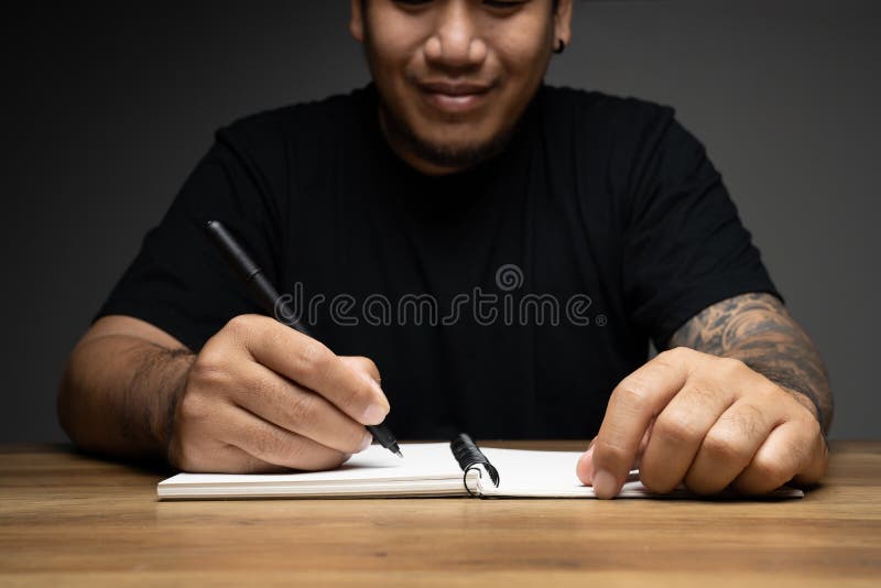 Asian Man Writing on a Note Book with Smile Face on Wooden Table ...