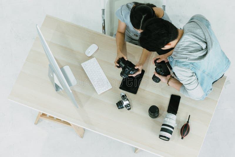 Asian Photographer and Model Sitting at the Table and Looking Pictures ...