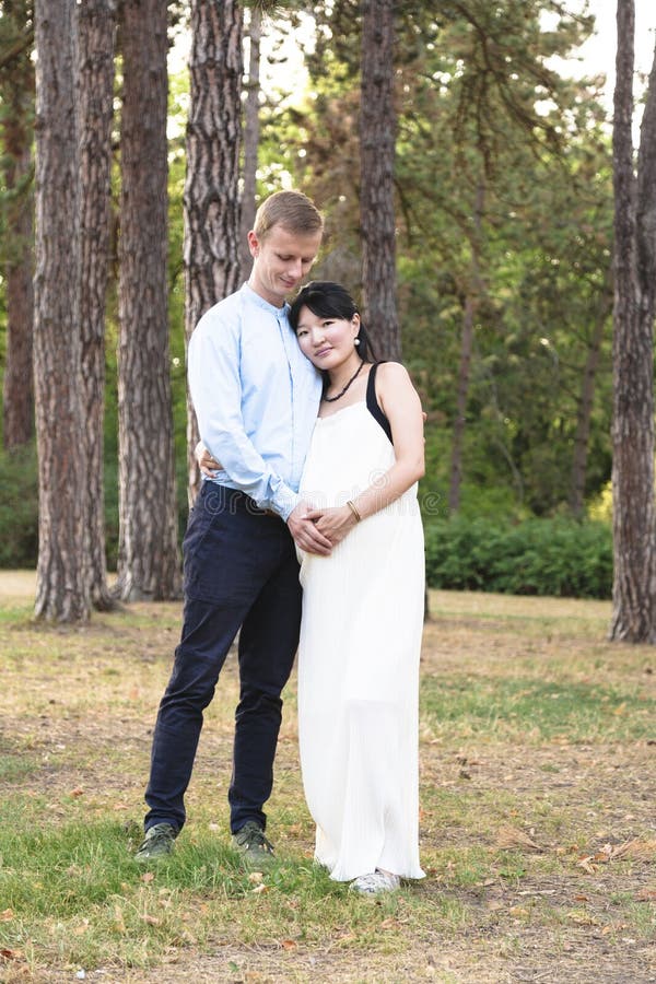 Handsome Man And Pregnant Woman Kissing Outdoor Near Tree Stock Image