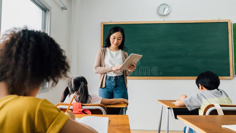 Asian School Teacher Using Digital Device with Children in Classroom at ...
