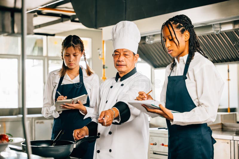 Asian Senior Chef in Uniform Teaches Cooking Techniques To Multiracial ...