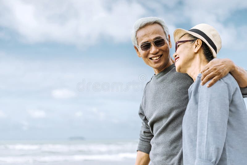 Asian Senior Couple Or Elderly People Walking And Siting At The Beach