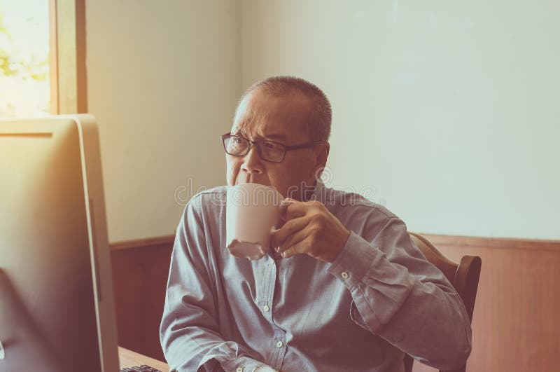 Asian Senior Man Serious and Drinking Coffee with Using Computer at ...