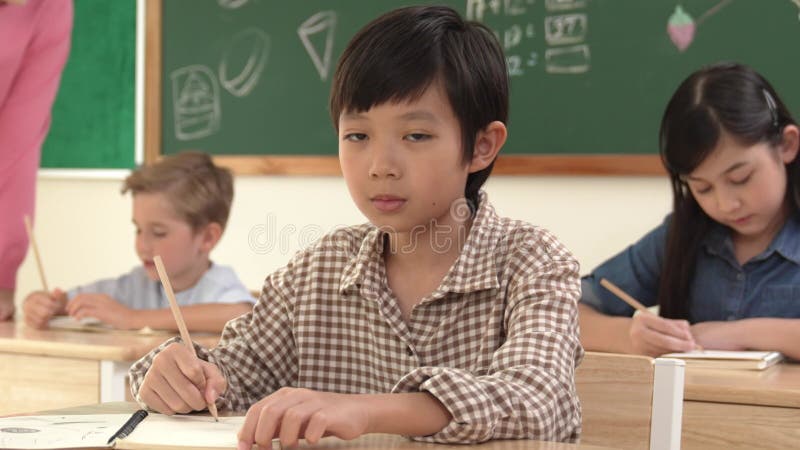 Boy Smiling To Camera while Student Writing Answer in Answer Sheet ...