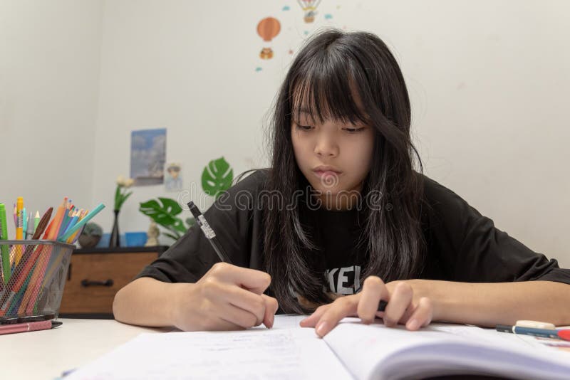 Asian Student Girl is Writing Homework and Reading Book at Desk Stock ...