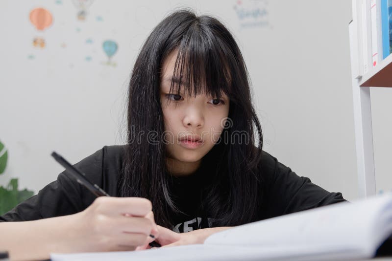 Asian Student Girl is Writing Homework and Reading Book at Desk Stock ...