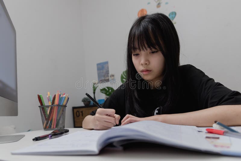Asian Student Girl is Writing Homework and Reading Book at Desk Stock ...