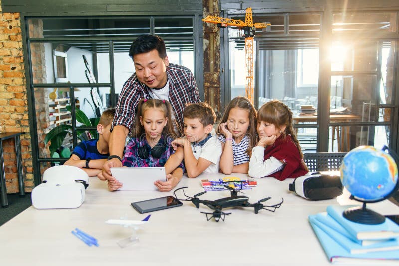 Asian Teacher Works with Five Young Pupils Using Digital Devices in ...
