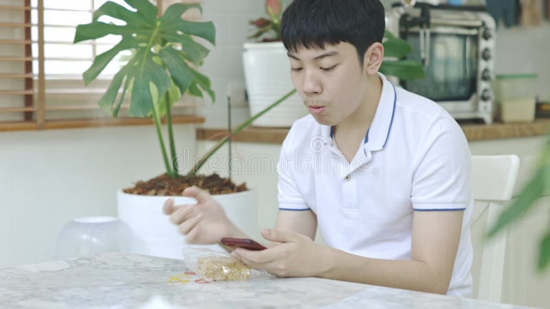 Asian Teen Boy Eating Snacks while Using the Phone at the Same Time ...