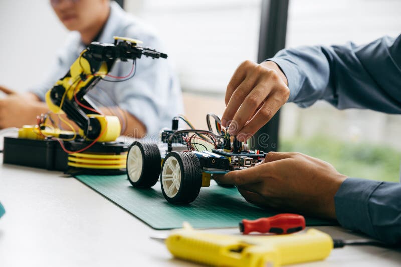 Two Asian Teenagers Constructing Robot Arm Project with Laptop in ...