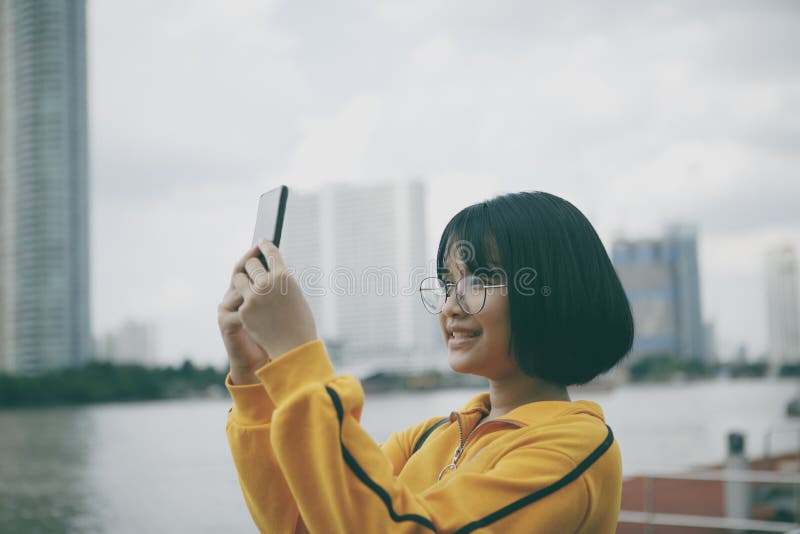 Asian Teenager Raising Mobile Phone and Looking into Device Screen ...