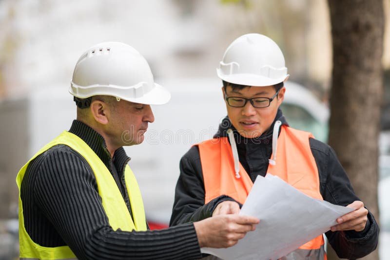 Asian Trainee Engineer at Work on Construction Site with the Senior ...