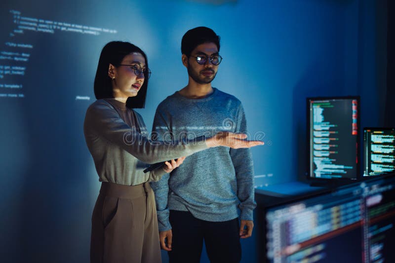 Asian Two Software Developers Engaged In Collaborative Coding Session With Code Projected Onto
