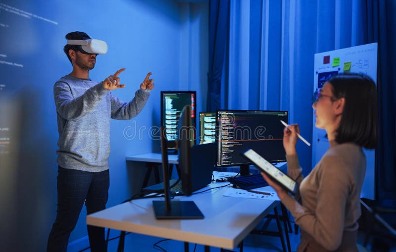 Asian UX Designer Works on a Tablet while a Colleague Tests a VR ...