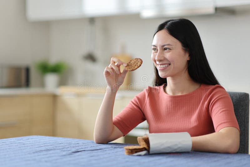 Asian Woman Eating Cookie in a Kitchen Stock Photo - Image of calories ...