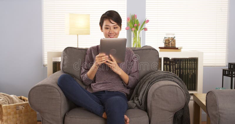 Asian Woman Happily Using Tablet on Sofa Stock Image - Image of ...
