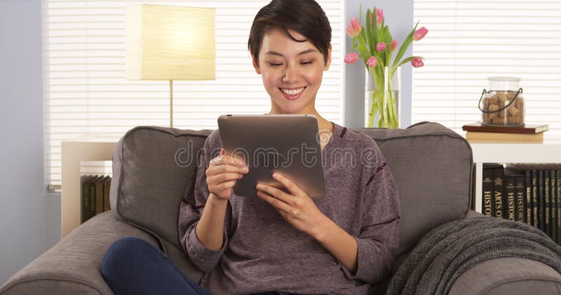 Asian Woman Happily Using Tablet on Sofa Stock Photo - Image of ...