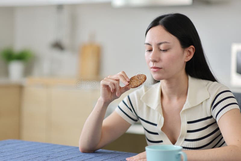 Asian Woman Looking at Cookie Ready To Eat in a Kitchen Stock Image ...