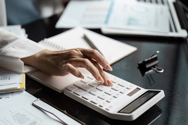 Asian Woman Using a Calculator while Managing Financial Documents in a ...