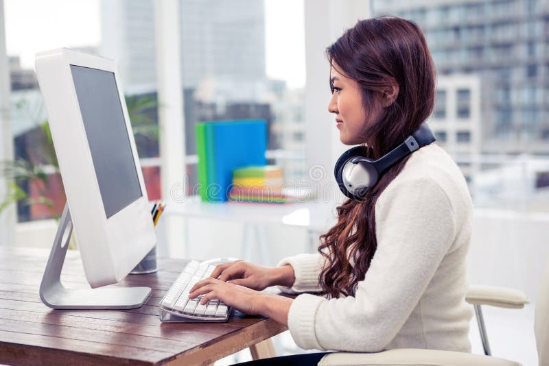 Asian Woman Using Computer with Headphones Around Neck Stock Photo ...