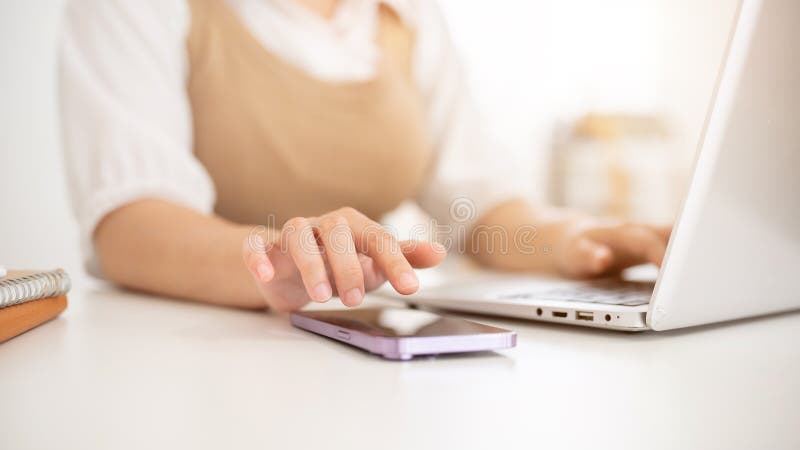 An Asian Woman Working Remotely from a Cafe, Multitasking, Using Her ...