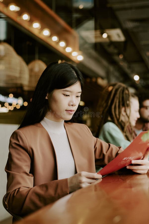 Reading Menu in Cozy Restaurant Setting with String Lights Stock Image ...
