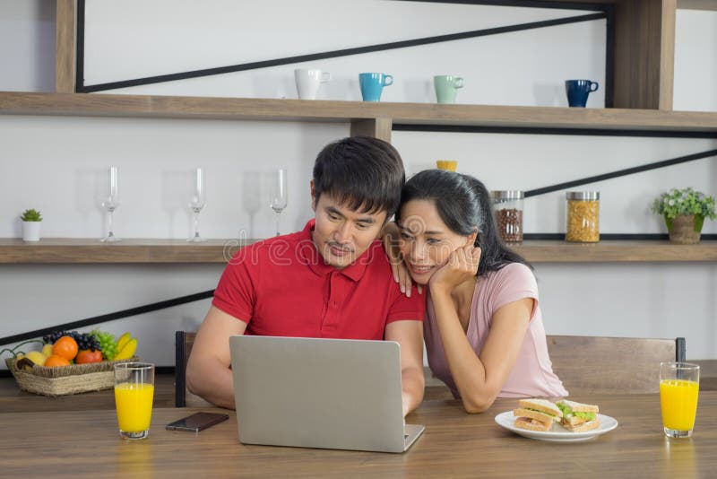 Asian Young Couples Sit at the Dining Table. they are Watching a Laptop ...