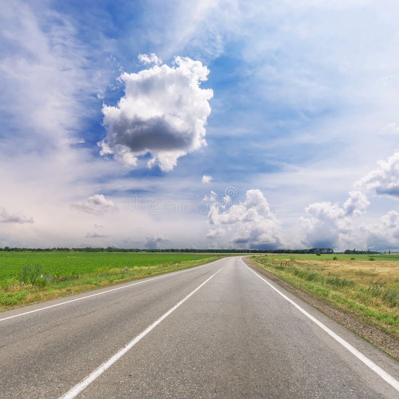 Asphalt Road To Horizon in Field Under Dramatic Clouds Stock Photo ...