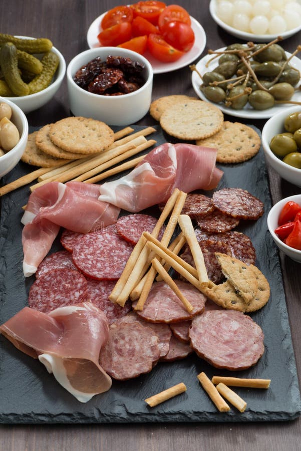 Assorted Meat Snacks and Pickles on a Blackboard, Vertical Stock Photo ...