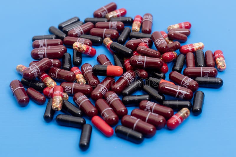 Assorted Red and Black Capsules on a Blue Surface, Close-up Stock Photo ...