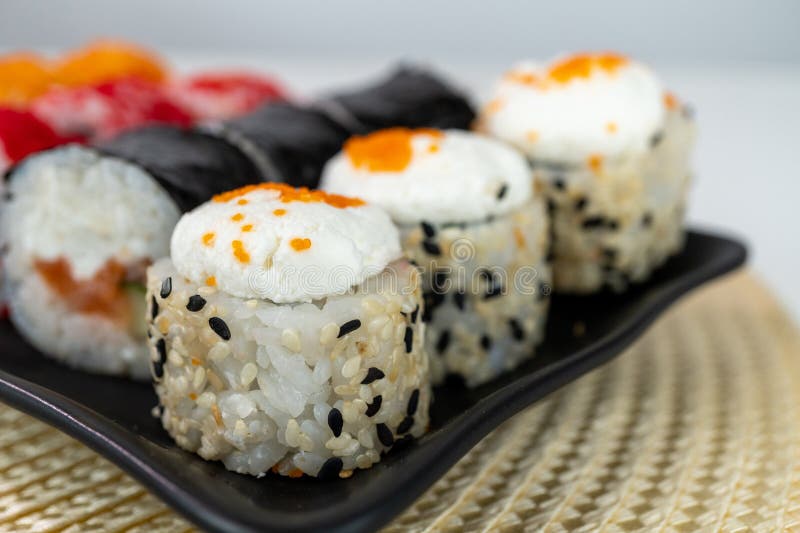Assorted Sushi Rolls with Cream Cheese and Fish Toppings on Black Plate ...