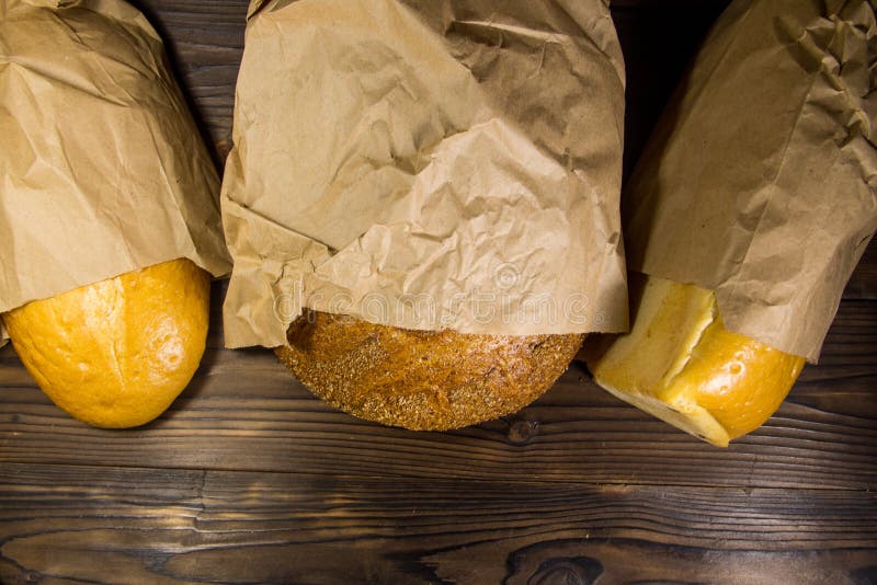 Assortment of Bread Packed in Paper on Wooden Table Stock Image - Image ...