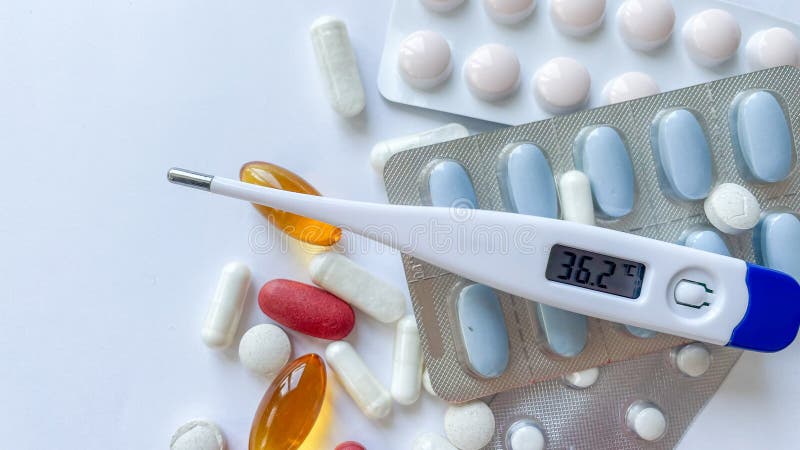 Assortment of Multicolored Pills, Capsules, and a Digital Thermometer ...