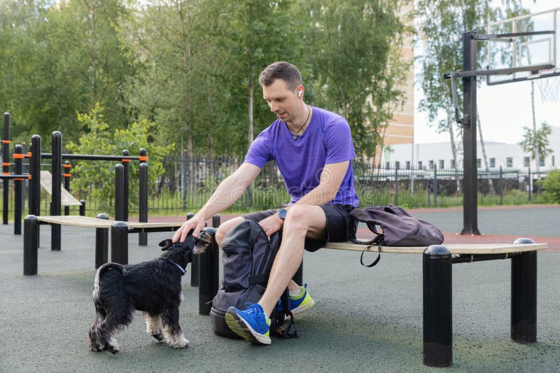 Athlete Interacting with Miniature Schnauzer on Park Bench Stock Photo ...