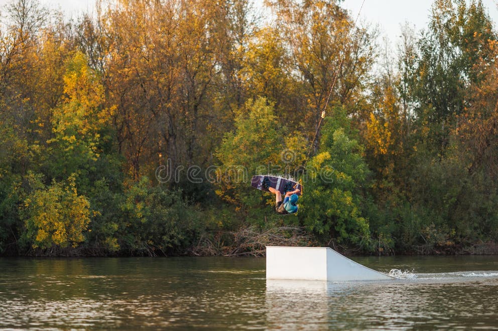 An Athlete Jumps from a Springboard. Wakeboard Park at Sunset Stock ...
