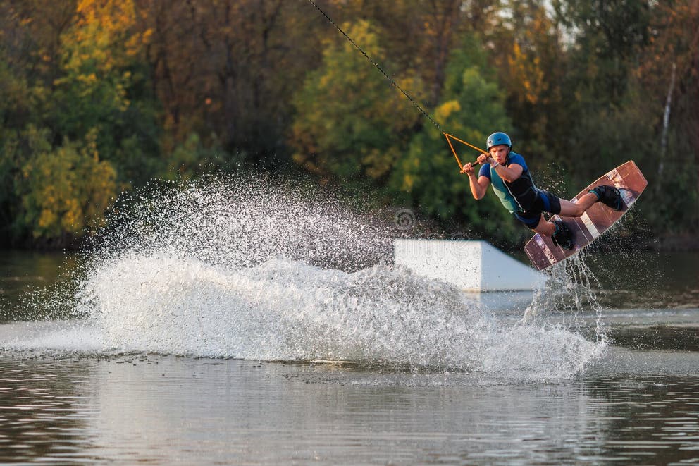 An Athlete Jumps from a Springboard. Wakeboard Park at Sunset Stock ...
