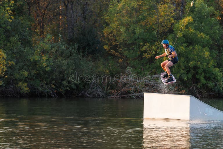 An Athlete Jumps from a Springboard. Wakeboard Park at Sunset Stock ...
