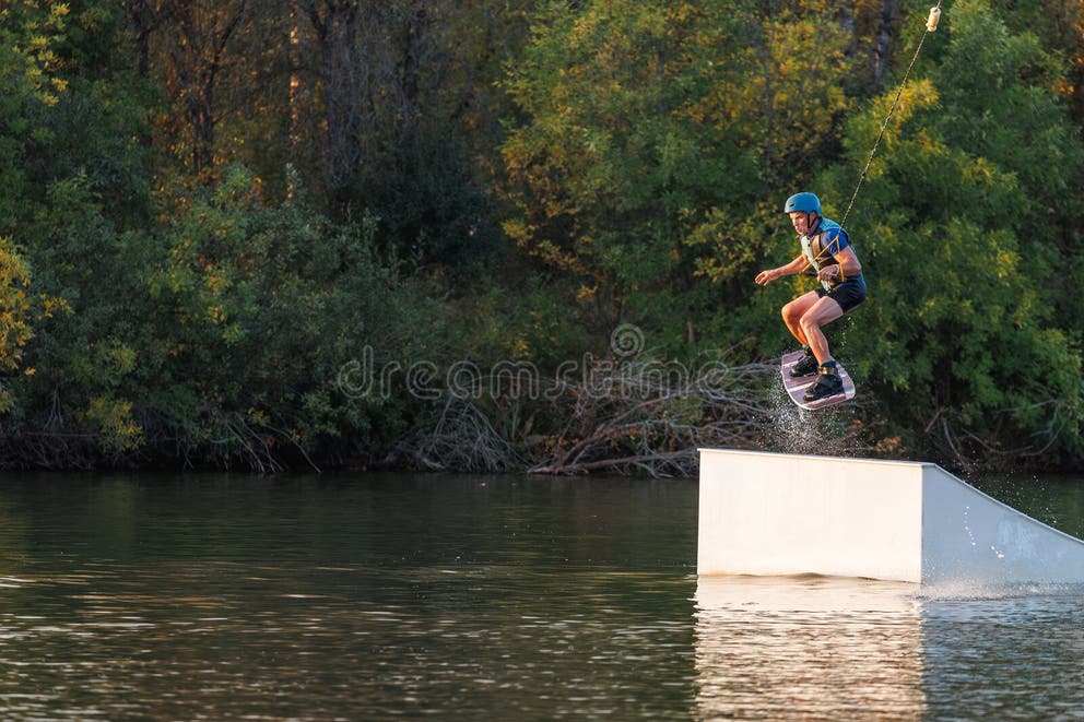 An Athlete Jumps from a Springboard. Wakeboard Park at Sunset Stock ...