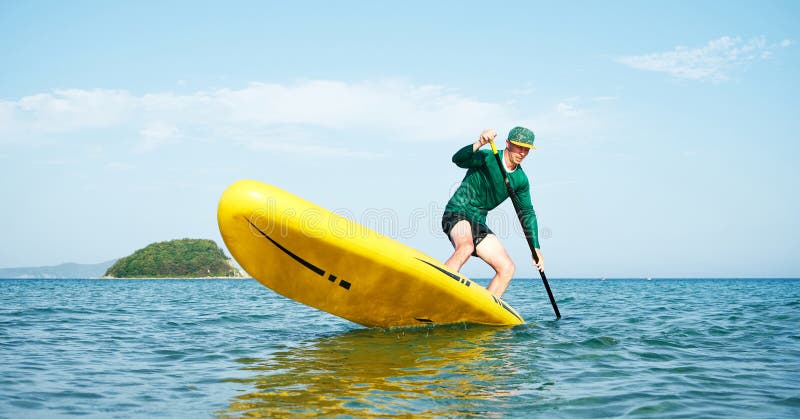 An Athlete on a Large Yellow SUP with a Paddle Performs a Turn Trick in ...