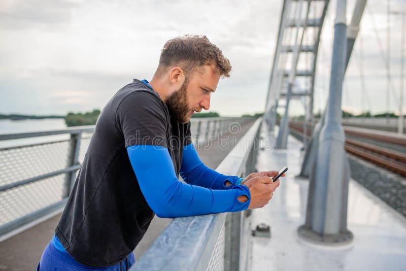 An Athlete with a Mobile Phone is Standing on the Bridge Stock Image ...
